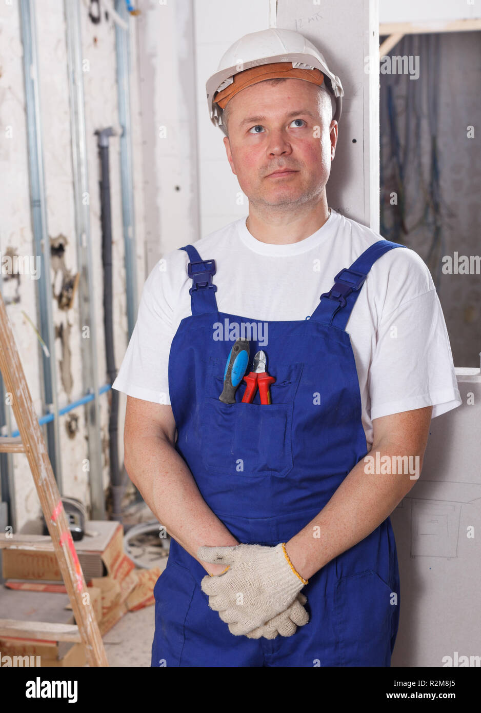 Portrait of tired male builder leaning on wall in repairable room Stock ...