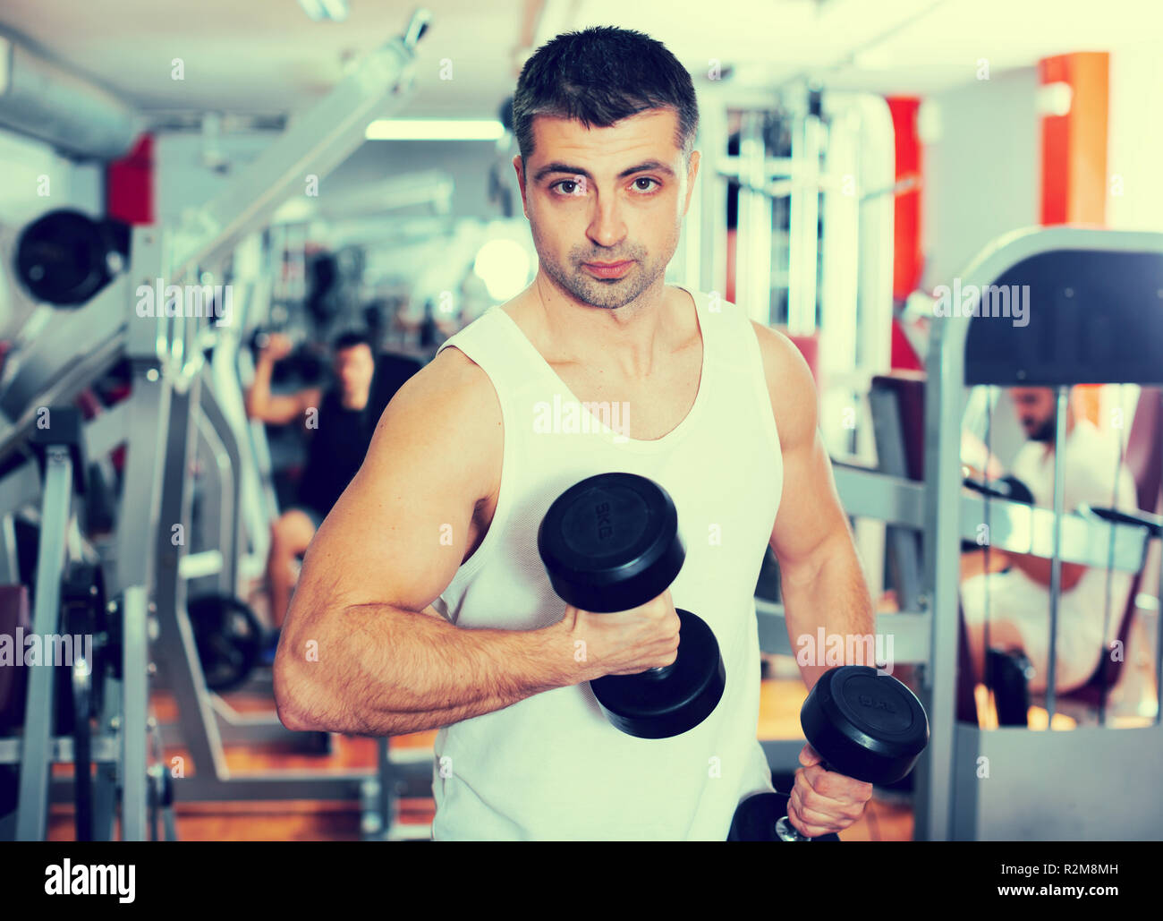 Concentrated sporty guy during workout in gym with dumbbells Stock ...
