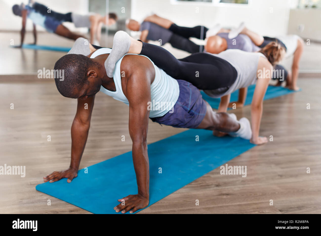 Group of sporty people doing stretching exercises in pairs before a ...