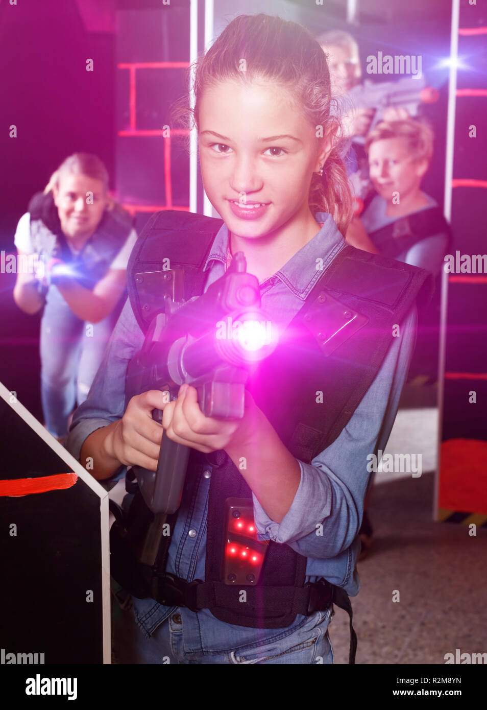 Emotional teen girl with a laser pistol playing laser tag with family ...