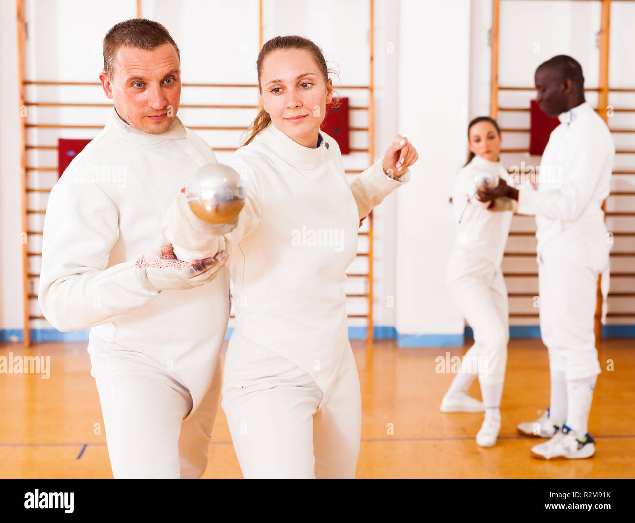 Girl fencer exercising new techniques with trainer at fencing room ...