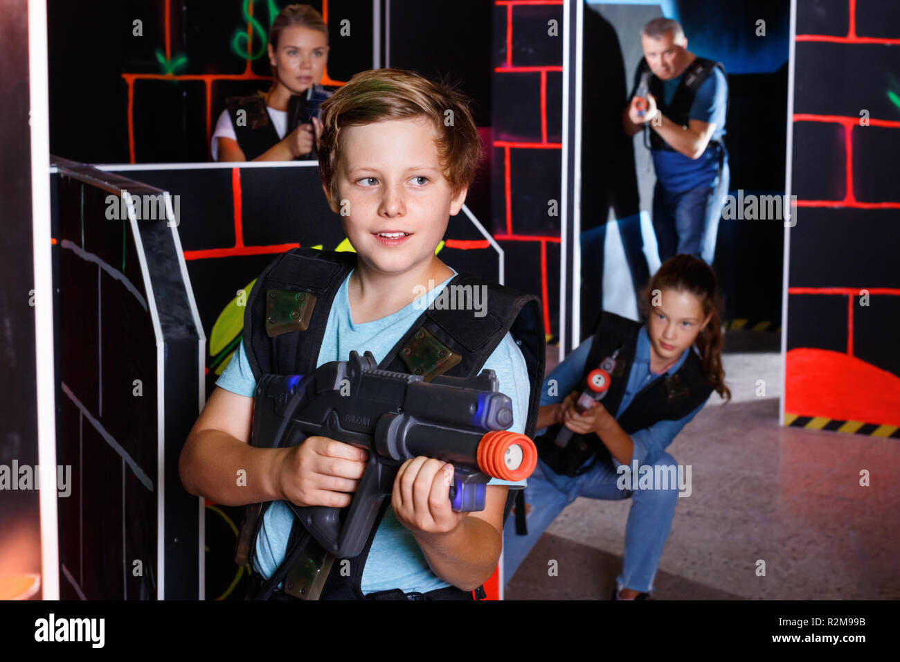 Excited glad positive smiling boy aiming laser gun at other players ...