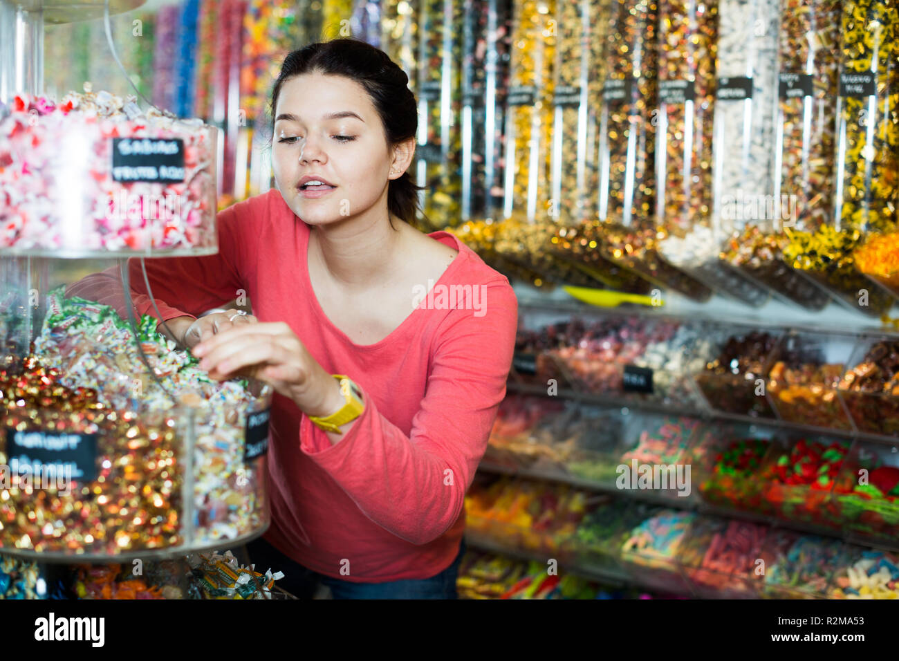 Happy brunette girl buying candies at shop Stock Photo - Alamy