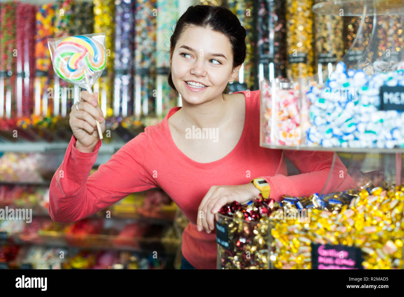 Happy brunette girl buying candies at shop Stock Photo - Alamy