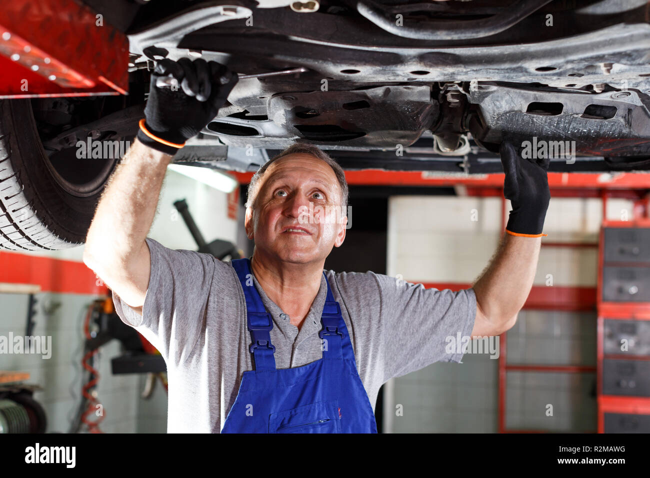 Professional mature man car mechanician repairing car in auto repair ...