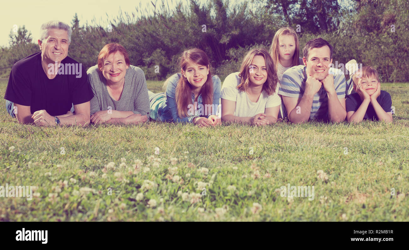 Cheerful smiling people of different ages taking photos on the lawn ...