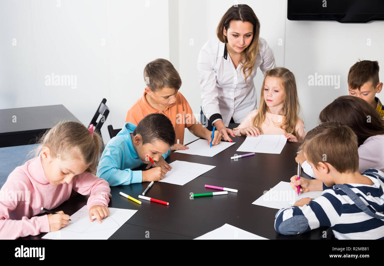 joyous little children with teacher drawing in classroom on the lesson ...