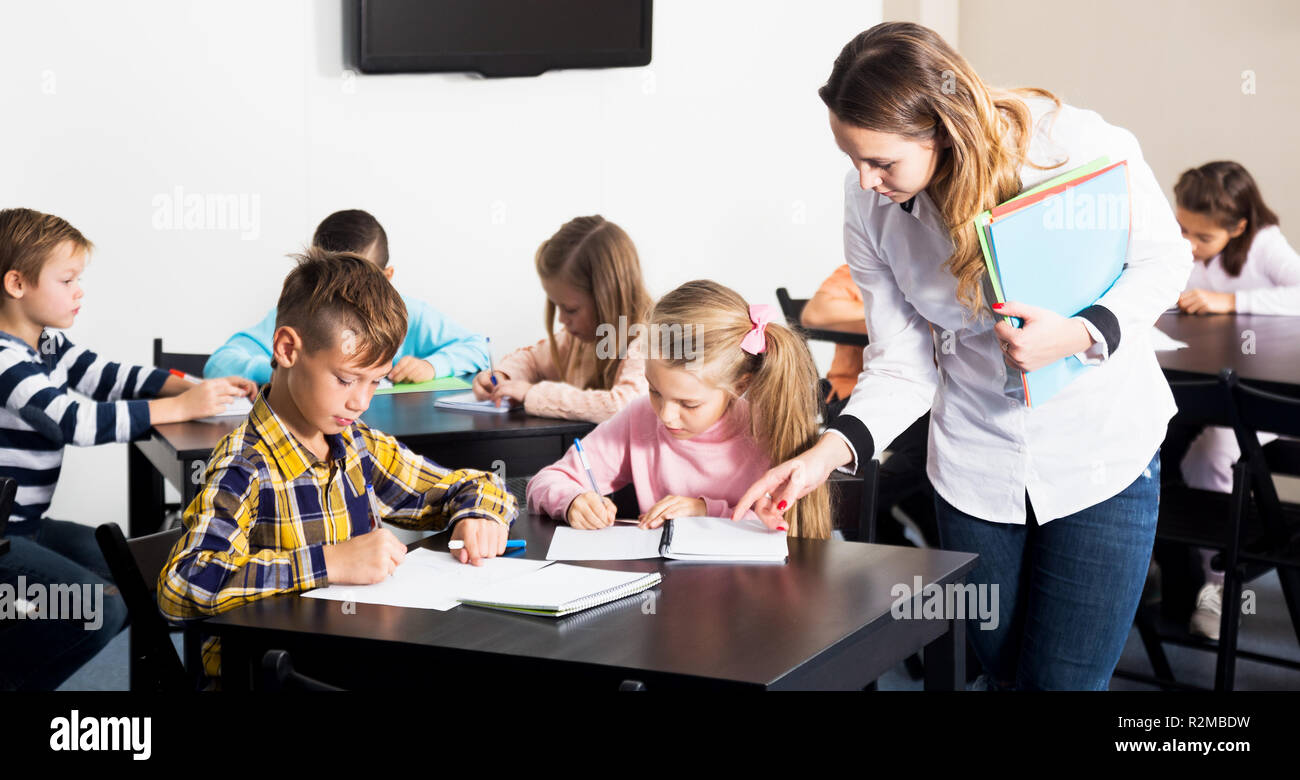 Glad professor and elementary age children at classroom Stock Photo - Alamy