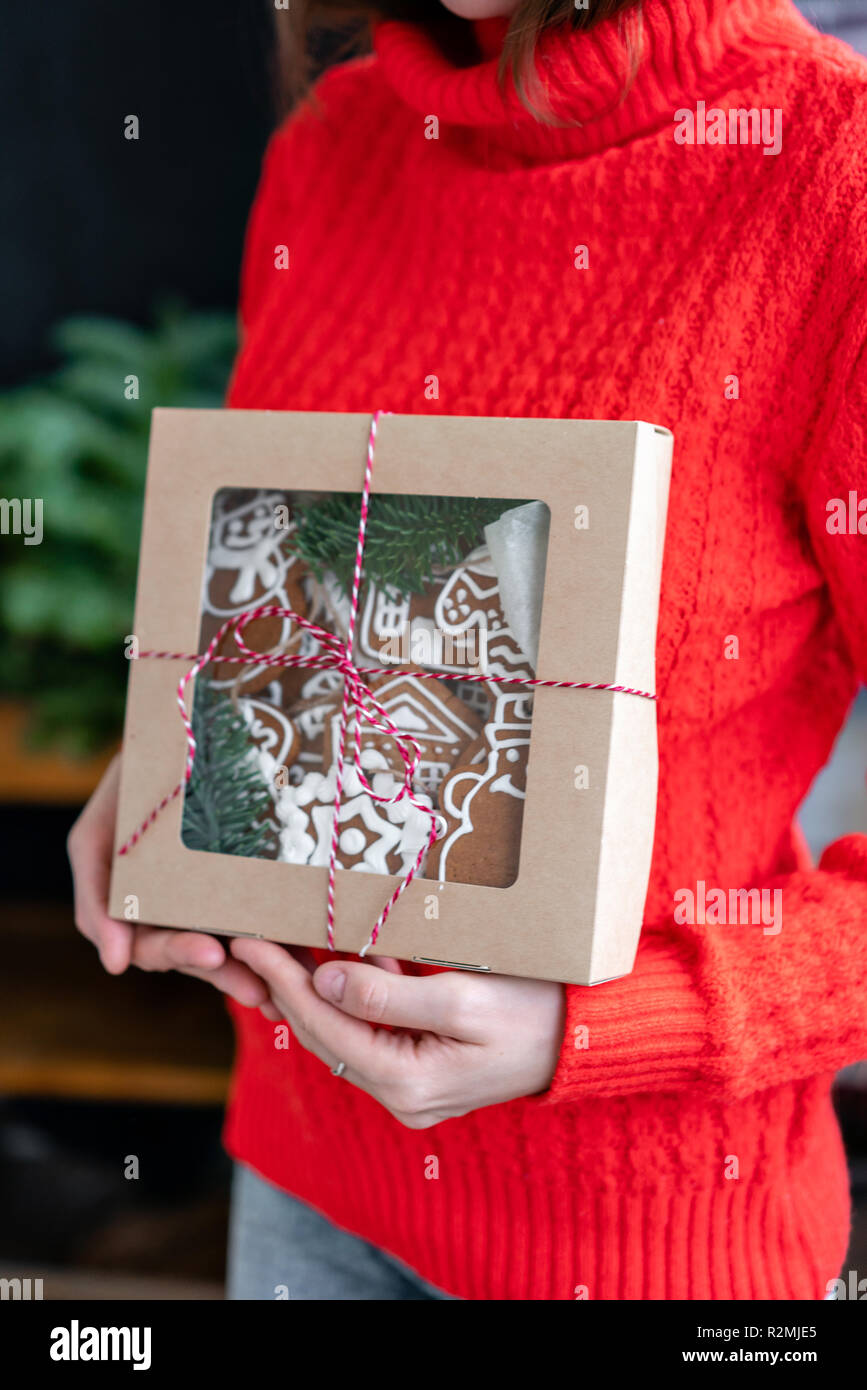Young woman in red sweater holding in his hand Christmas gift, homemade ...