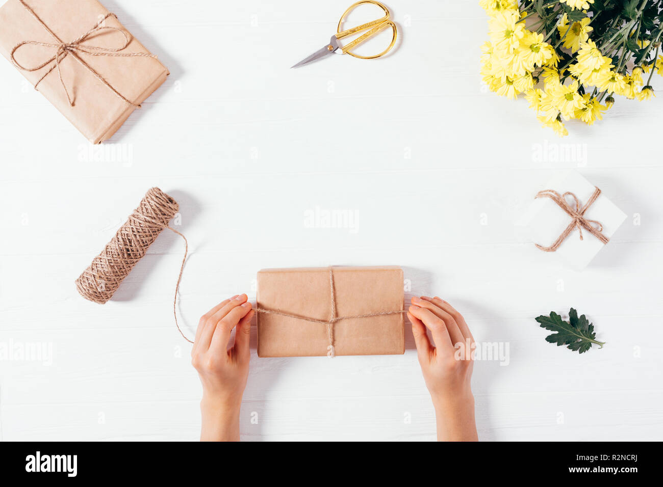 Flat lay arrangement female's hands tying gift box with twine among ...