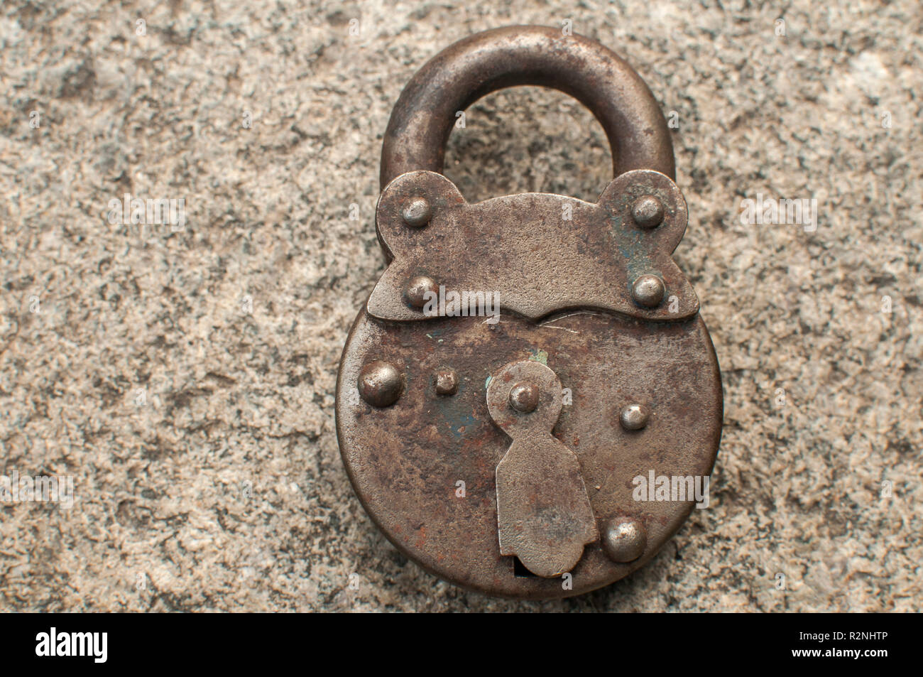 Old weathered grunge retro locked padlock closeup on solid stone ...