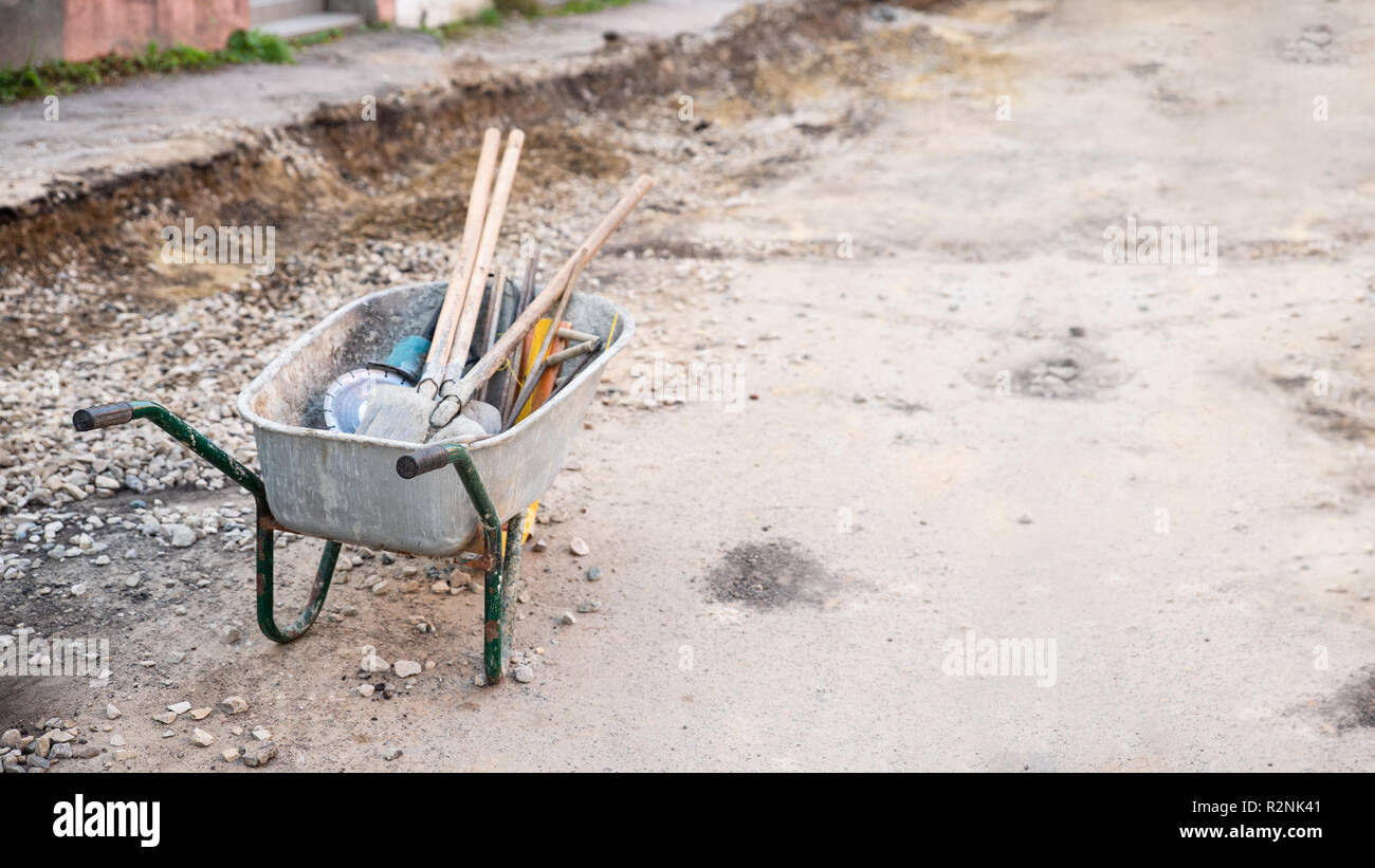 Wheelbarrow with working tool in the middle of road, road repair work ...