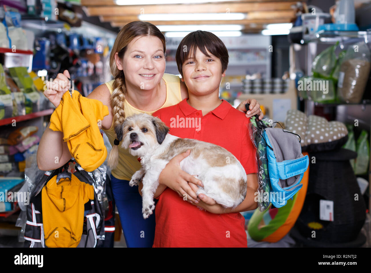 Female customer with son buying new dog clothes in store for their pup ...