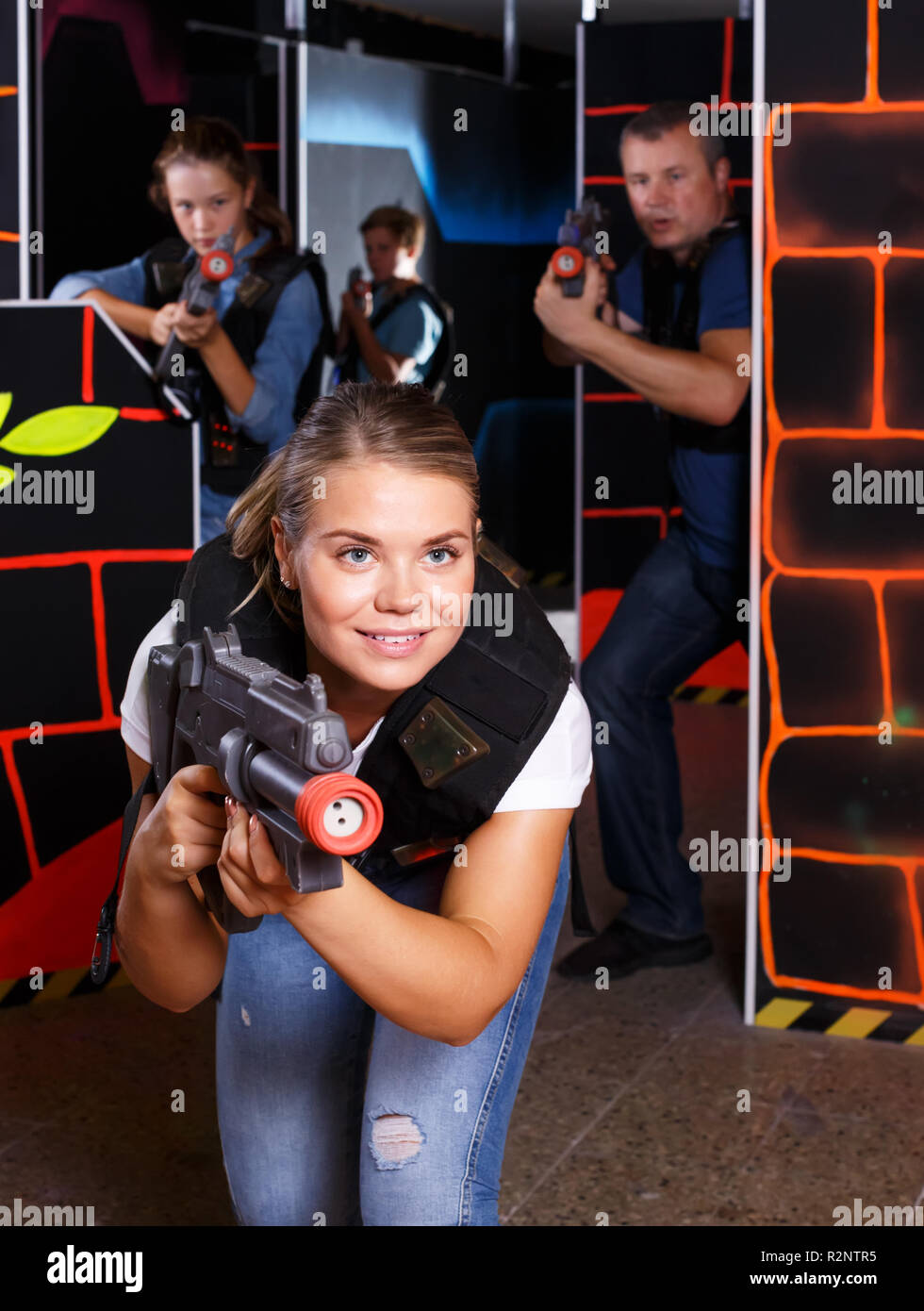 Portrait of young emotional woman with laser gun having fun with family ...