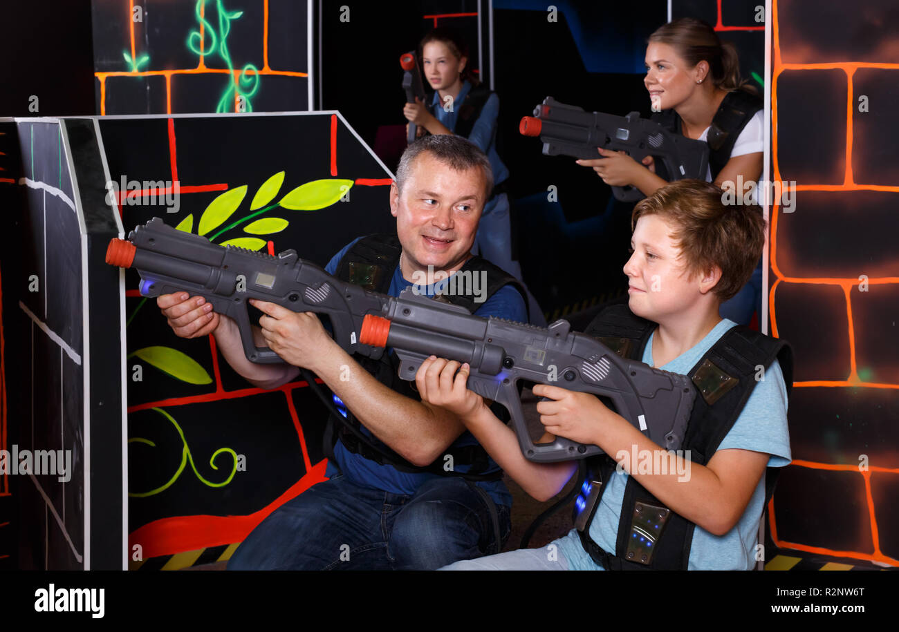 Glad teenager boy and his father aiming laser guns at other players ...
