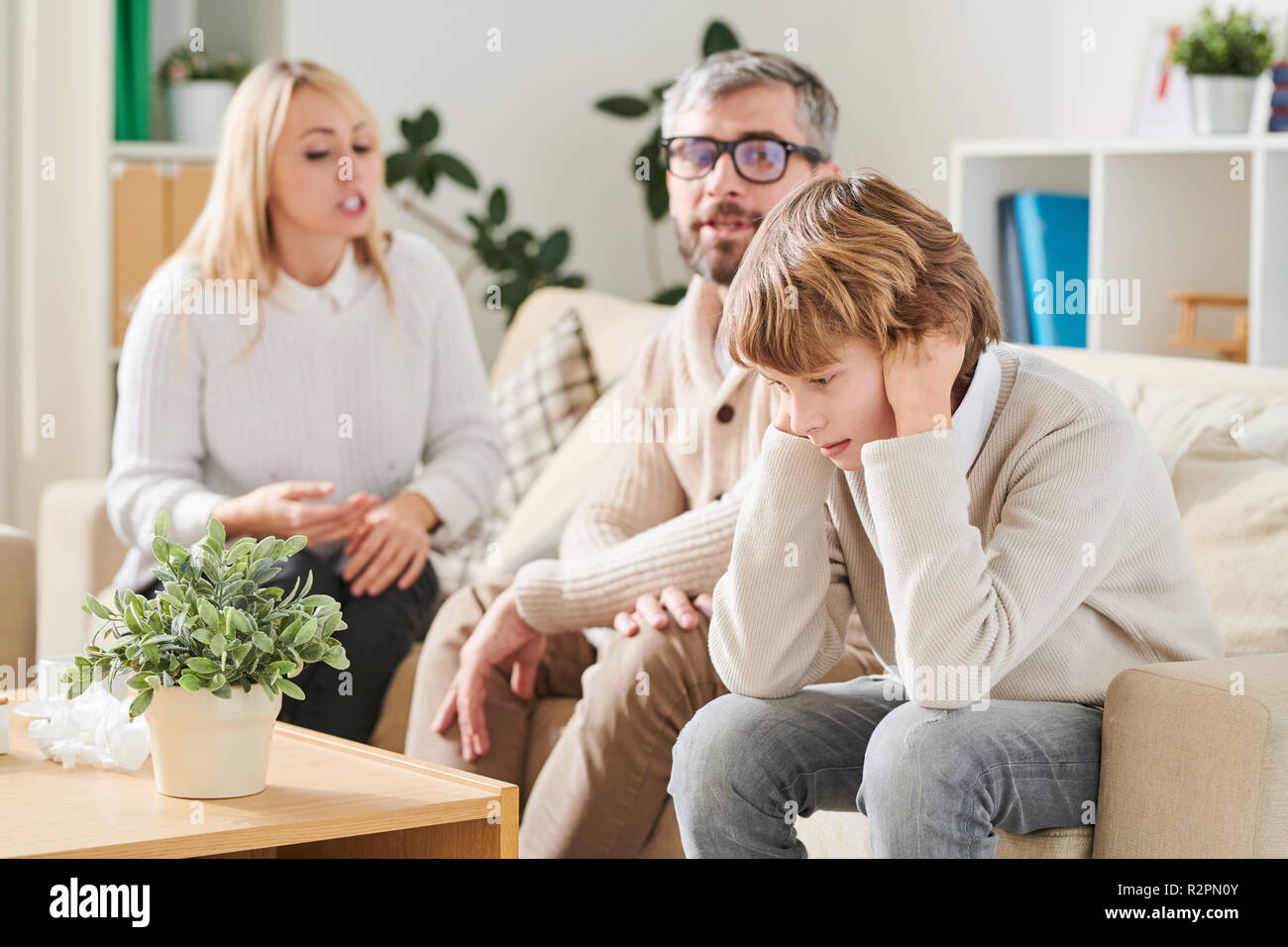 Depressed son covering ears to avoid parents quarrel Stock Photo - Alamy