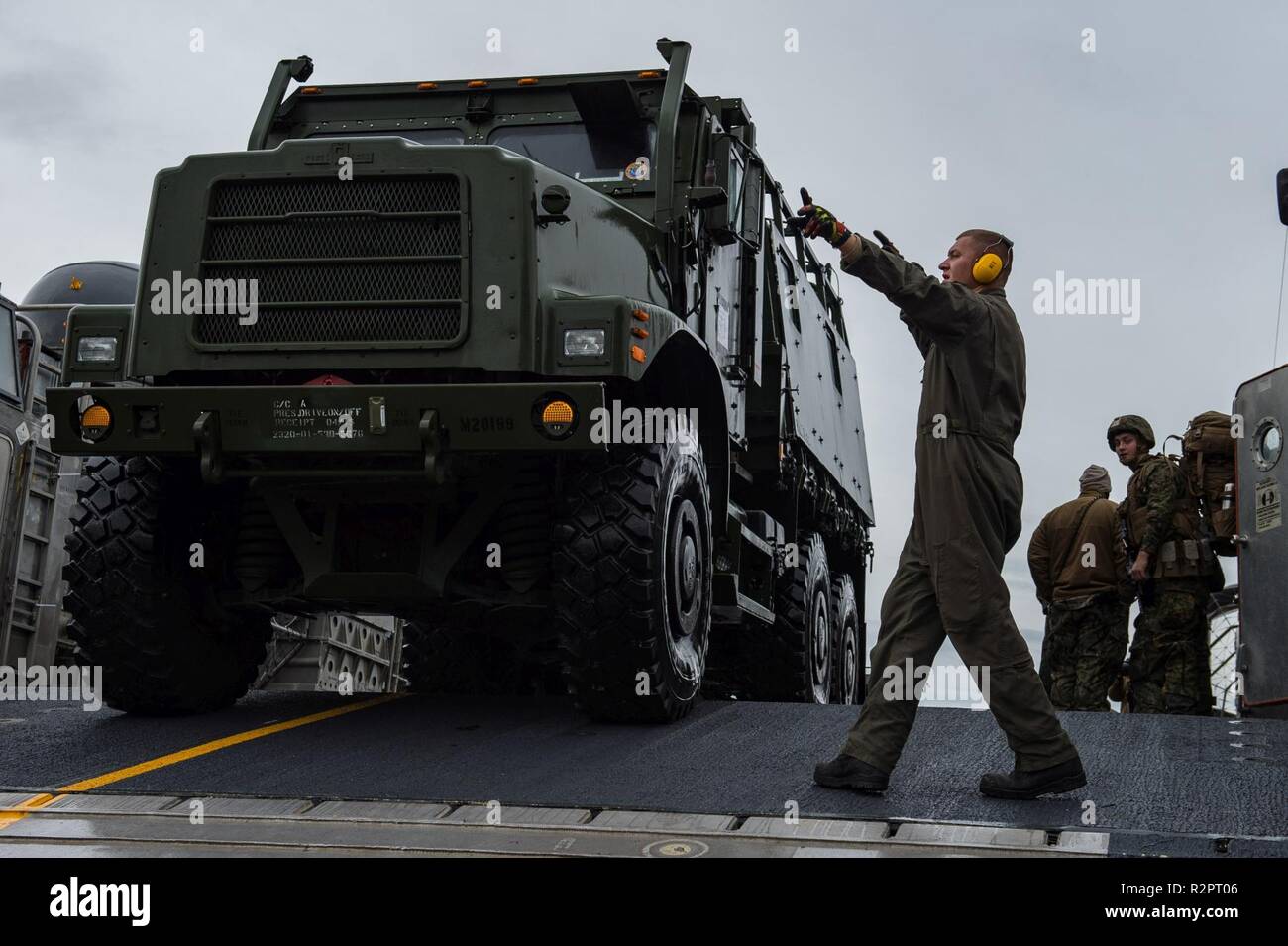 A U.S. Navy sailor directs a vehicle on a U.S. Marine Landing Craft Air ...