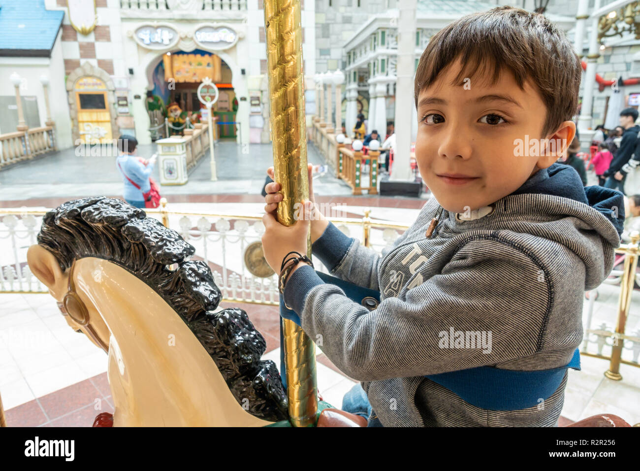 A happy young boy riding on a merry-go-round Stock Photo - Alamy