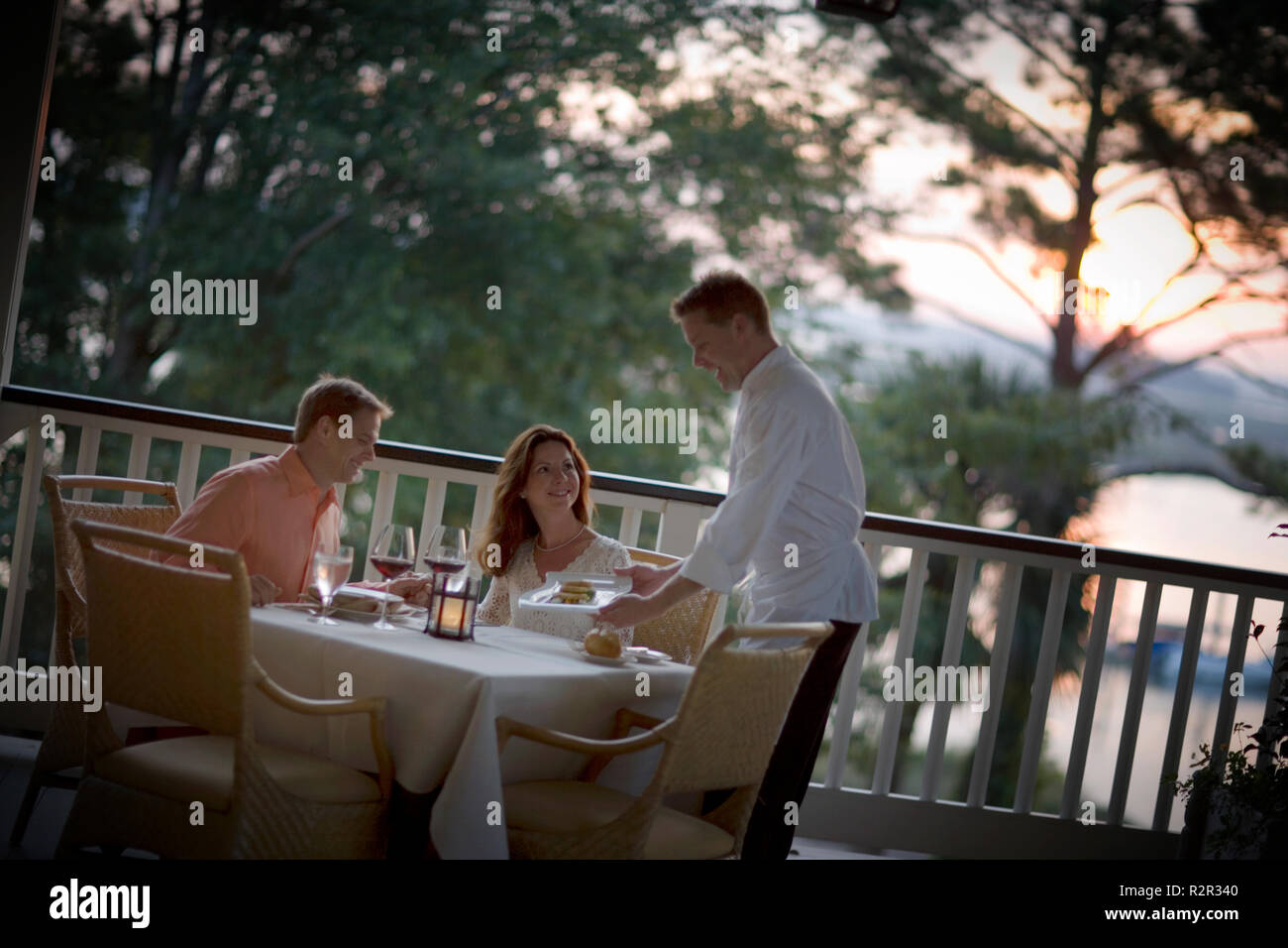 Happy mid-adult couple being served by a waiter at an outdoor ...