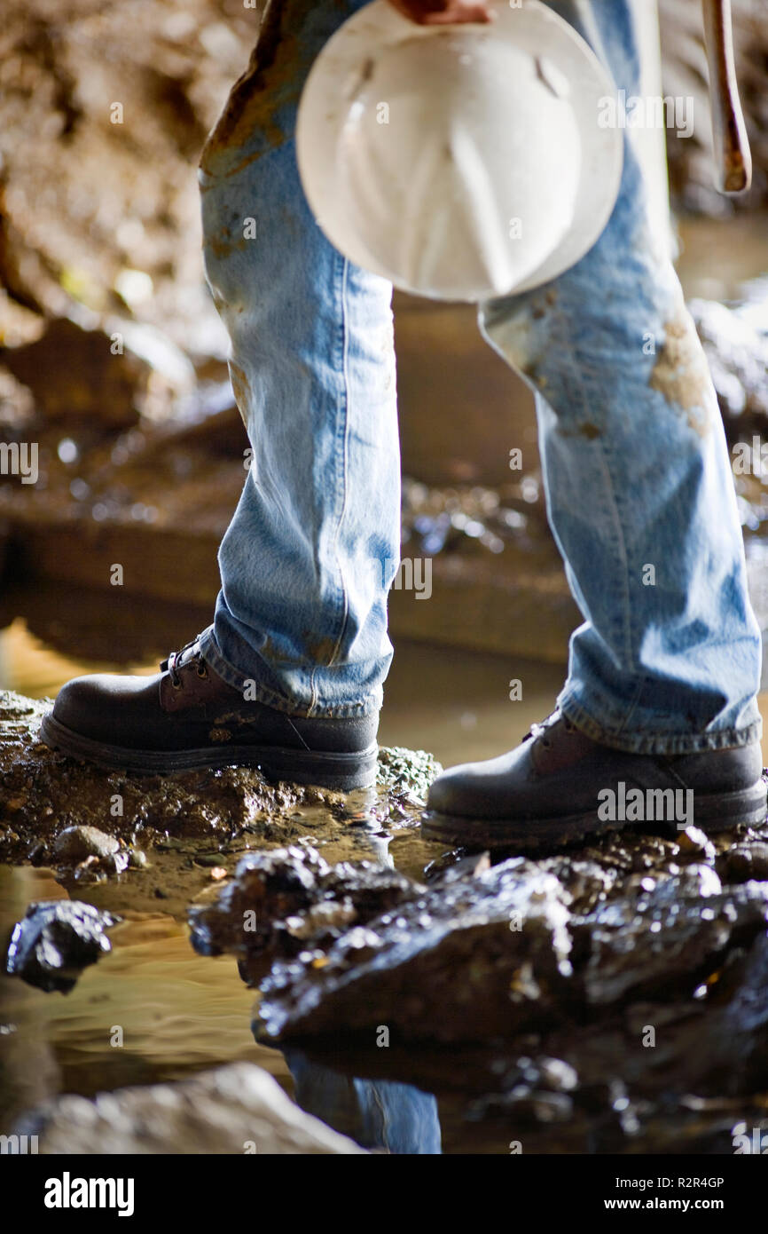 Legs of a construction worker standing in a puddle on a building site ...