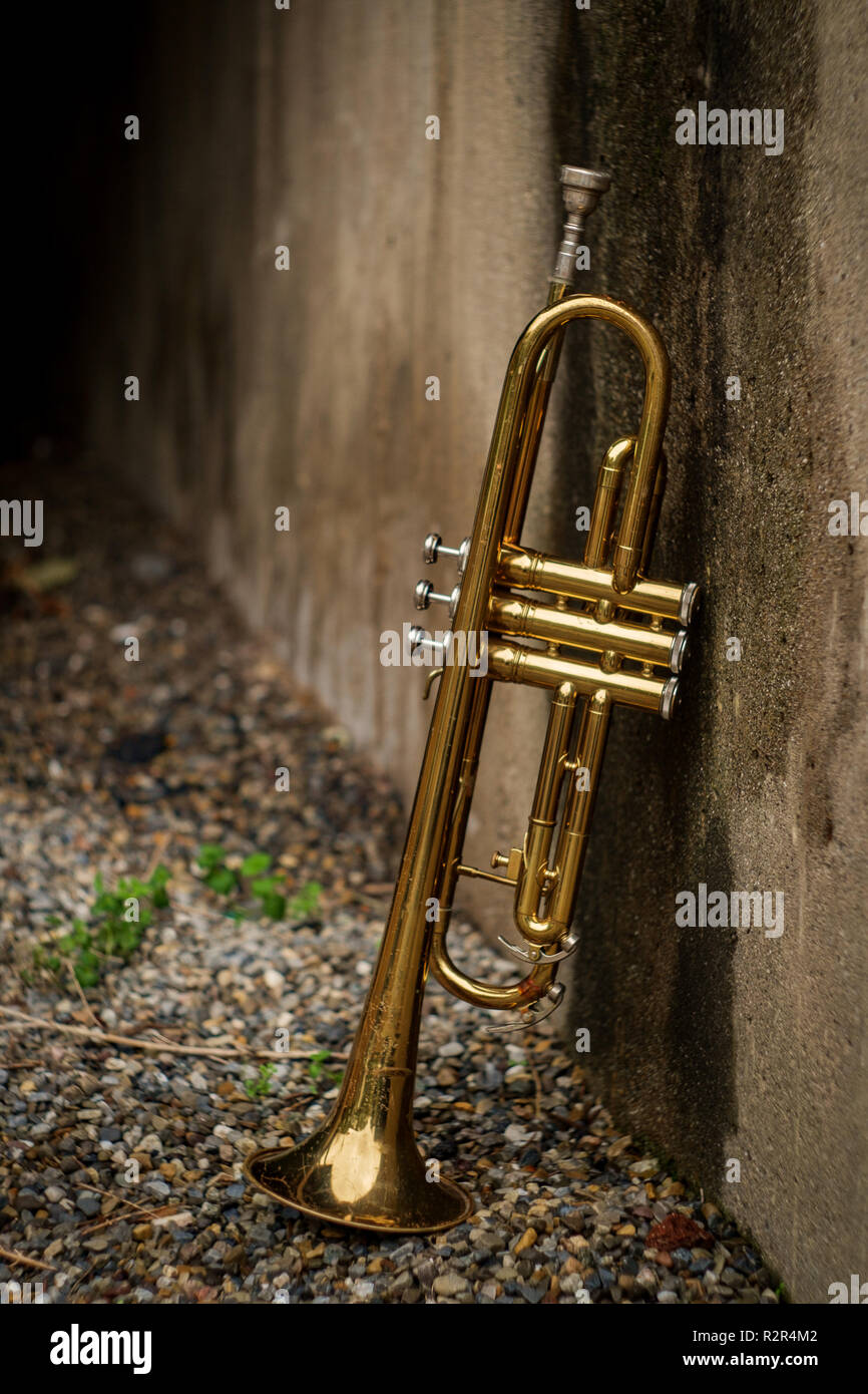 Old rusty Jazz instrument trumpet leaning against alley building ...