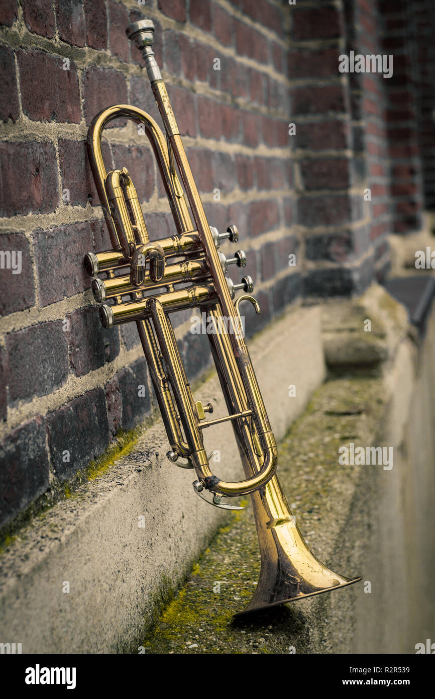 Old rusty Jazz instrument trumpet leaning against brick wall building ...