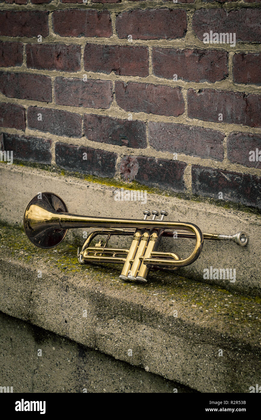 Old rusty Jazz instrument trumpet leaning against brick wall building ...