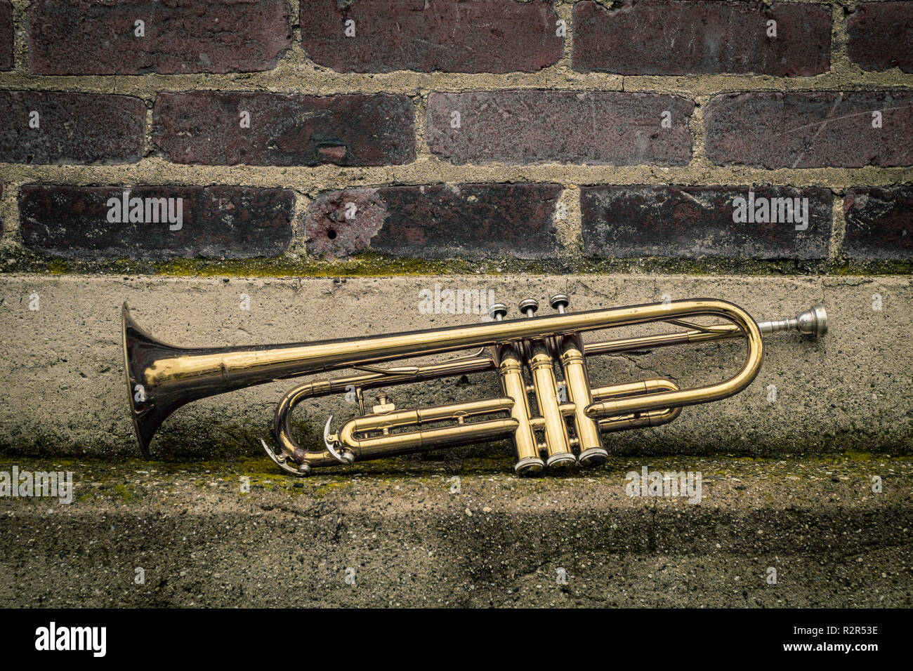 Old rusty Jazz instrument trumpet leaning against brick wall building ...