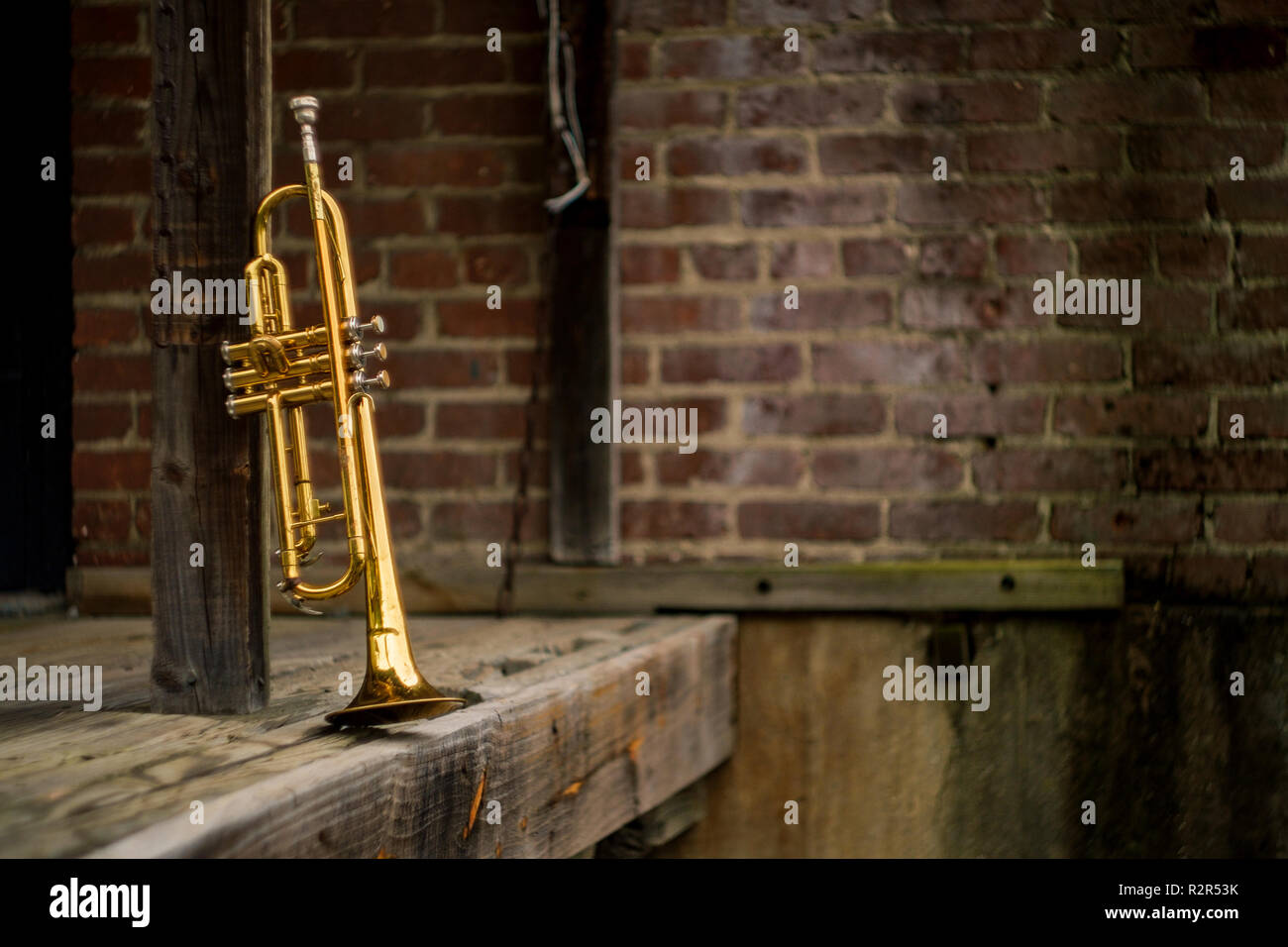 Old rusty Jazz instrument trumpet leaning against brick wall building ...