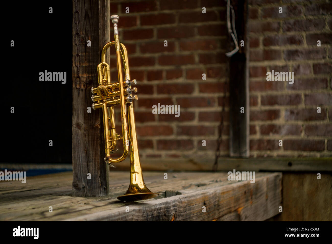 Old rusty Jazz instrument trumpet leaning against brick wall building ...