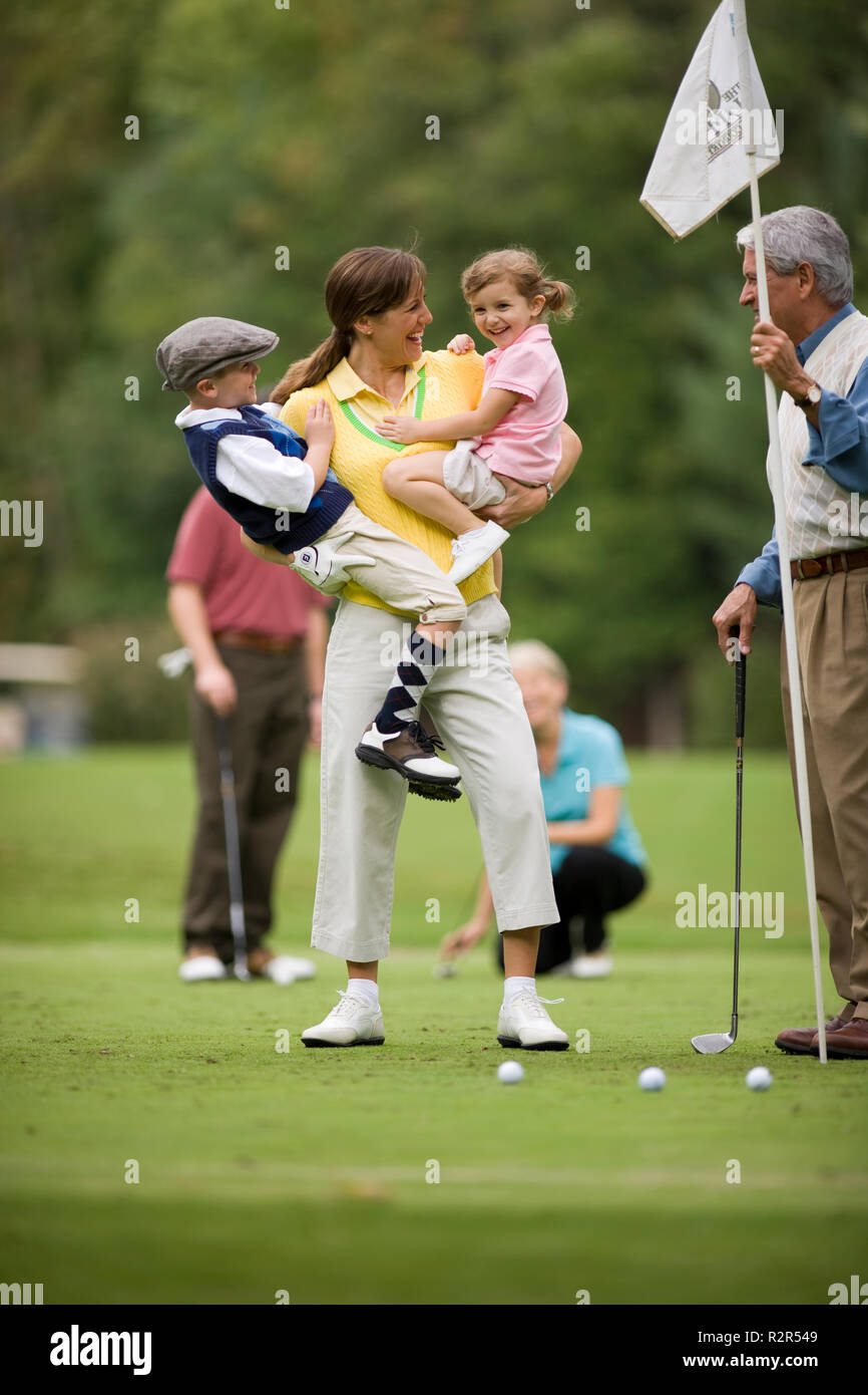 Mother holding two children on golf course Stock Photo - Alamy