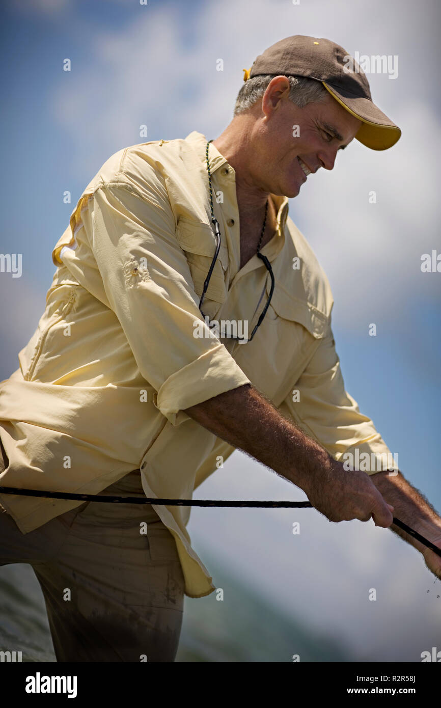Man pulling rope from water Stock Photo - Alamy