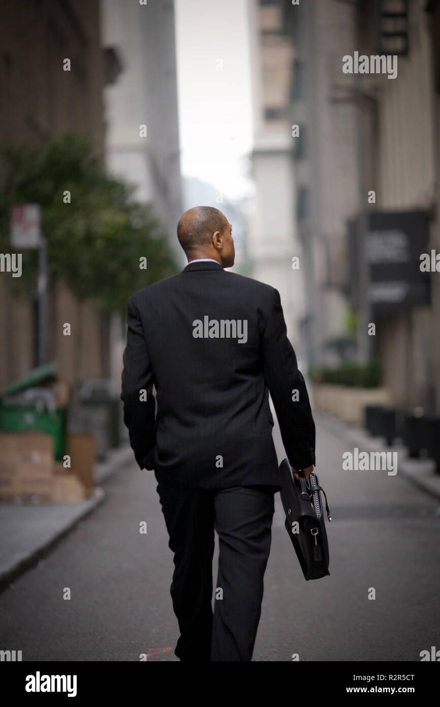 Confident mid-adult businessman carrying a briefcase while walking down ...
