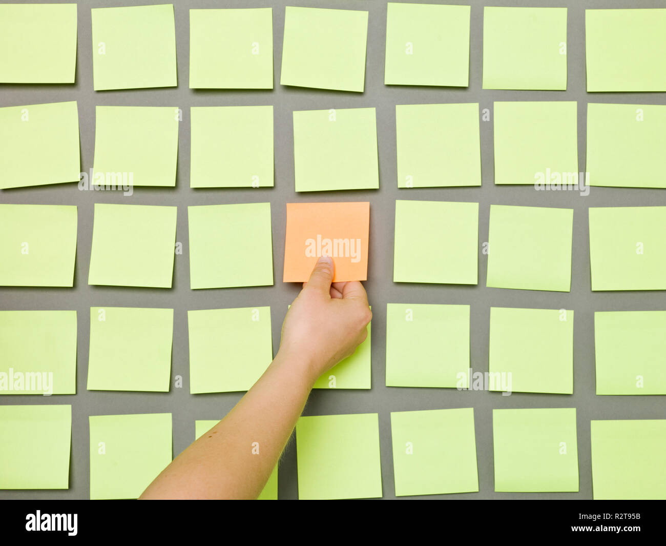Hand taking a Adhesive Note from a grey wall Stock Photo - Alamy