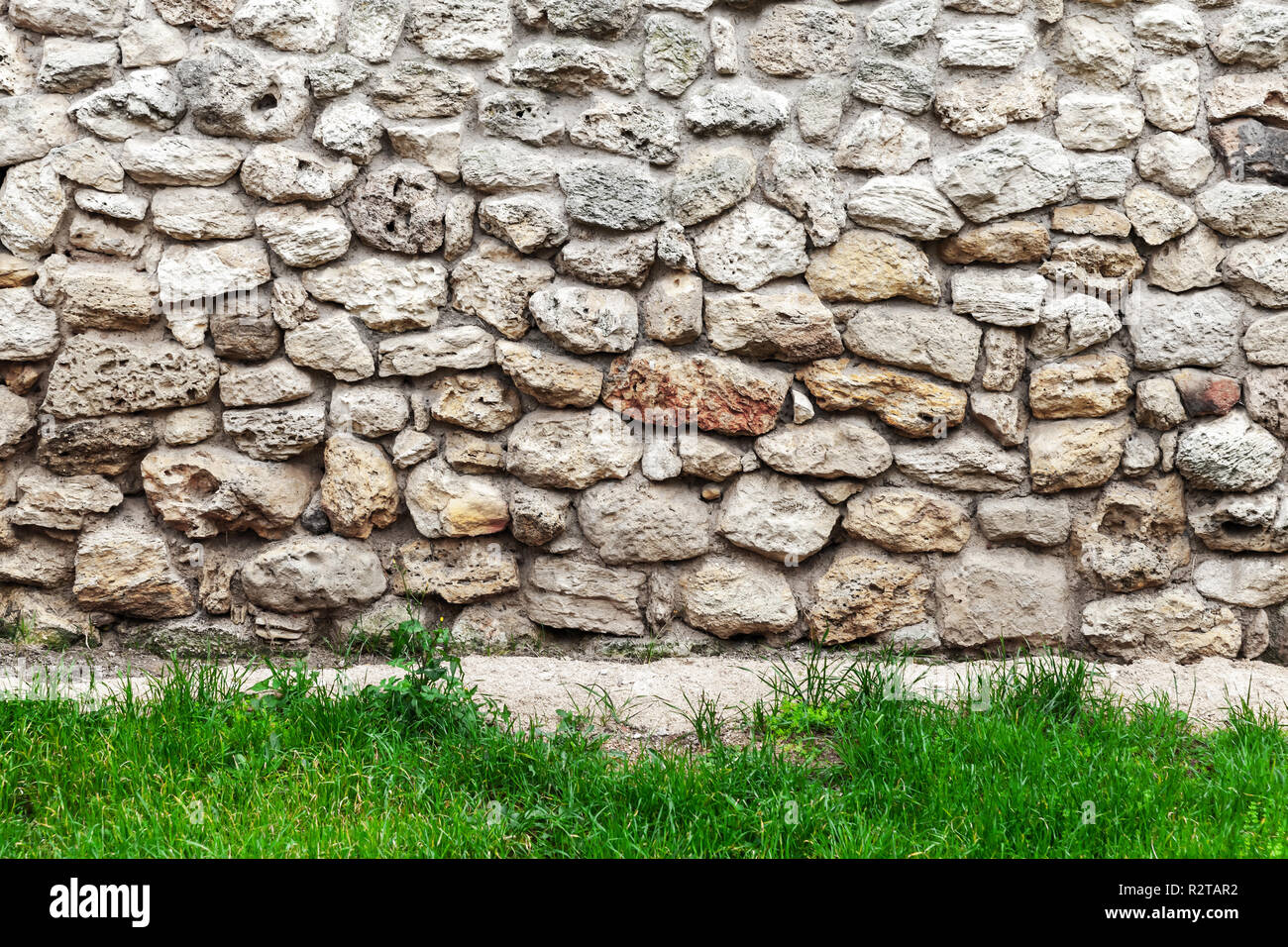 Old stone wall and fresh green grass, front view, background photo ...
