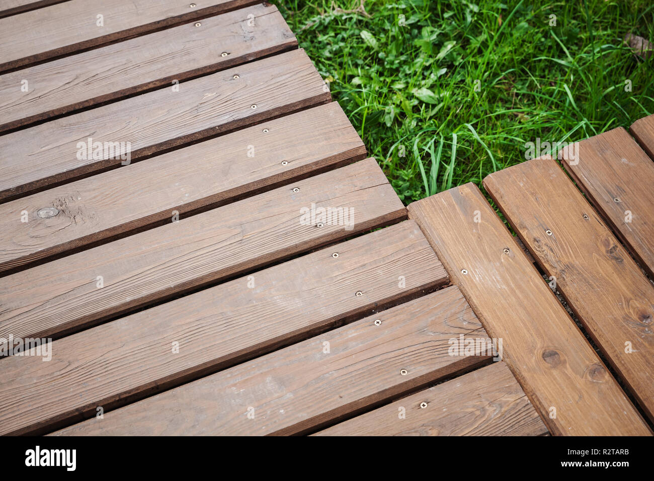 Corner of wooden boardwalk over lawn with green grass, modern park ...