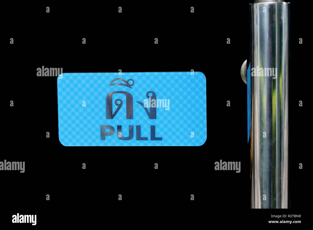closeup image of pull sign in both thai and english languages on dark ...