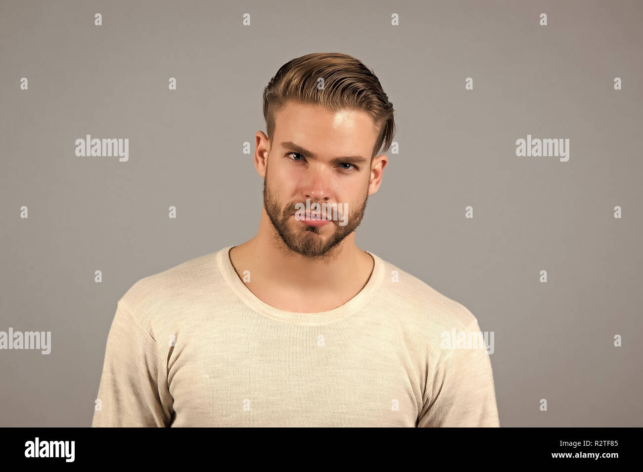 Man with unshaven face hair and fashionable haircut in white shirt pose ...