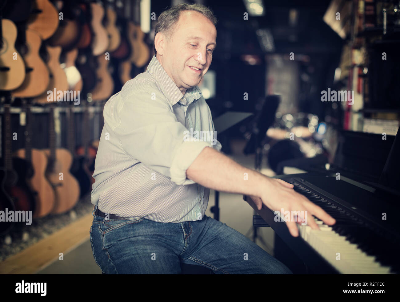 Adult man is playing on music keyboard in music store Stock Photo - Alamy