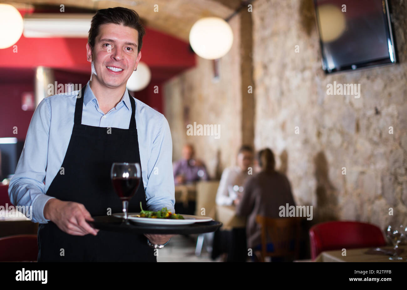 Portrait of smiling waiter with serving tray meeting cafe guests Stock ...