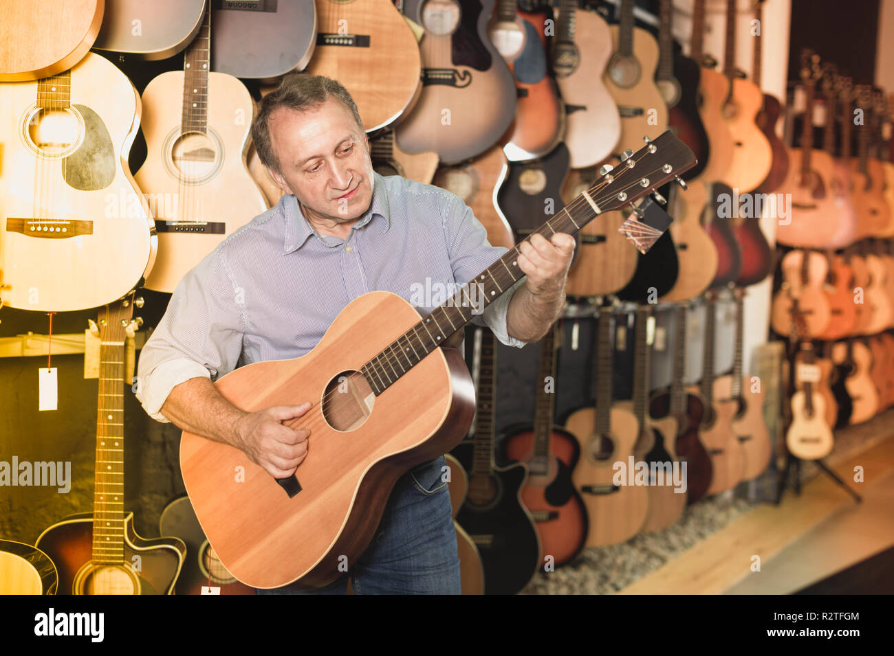 Adult glad cheerful positive guitarist is playing on acoustic guitar in ...
