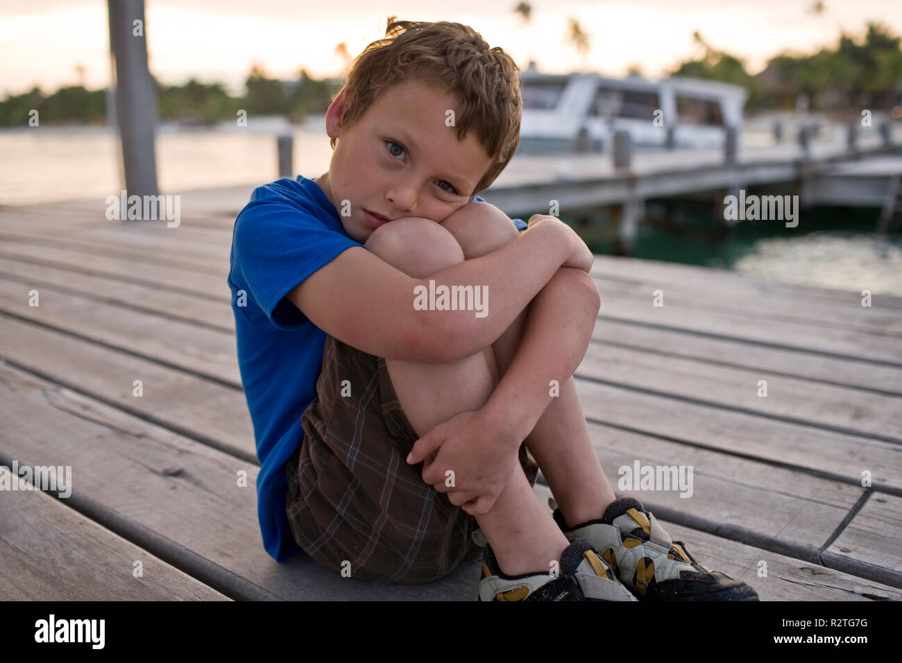Boy sitting on pier Stock Photo - Alamy