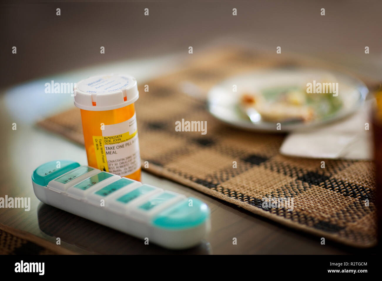 Pill bottle and pill case on a table with meal in the background Stock ...