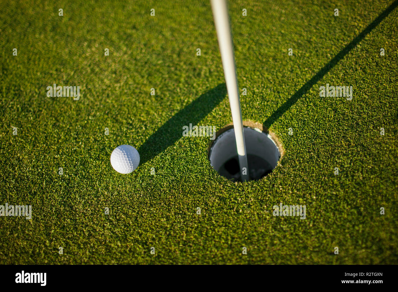 Single golf ball sitting near a hole on a golf course Stock Photo - Alamy