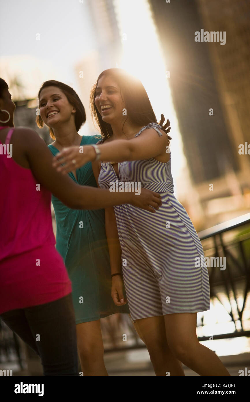 Two smiling friends reaching their arms out to hug another friend in ...