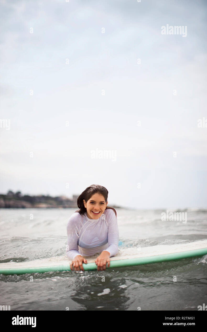Young woman floating on her surfboard at the beach Stock Photo - Alamy