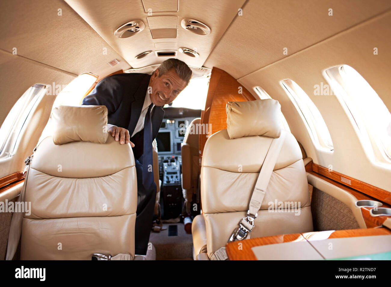 Businessman smiling on a private jet Stock Photo - Alamy