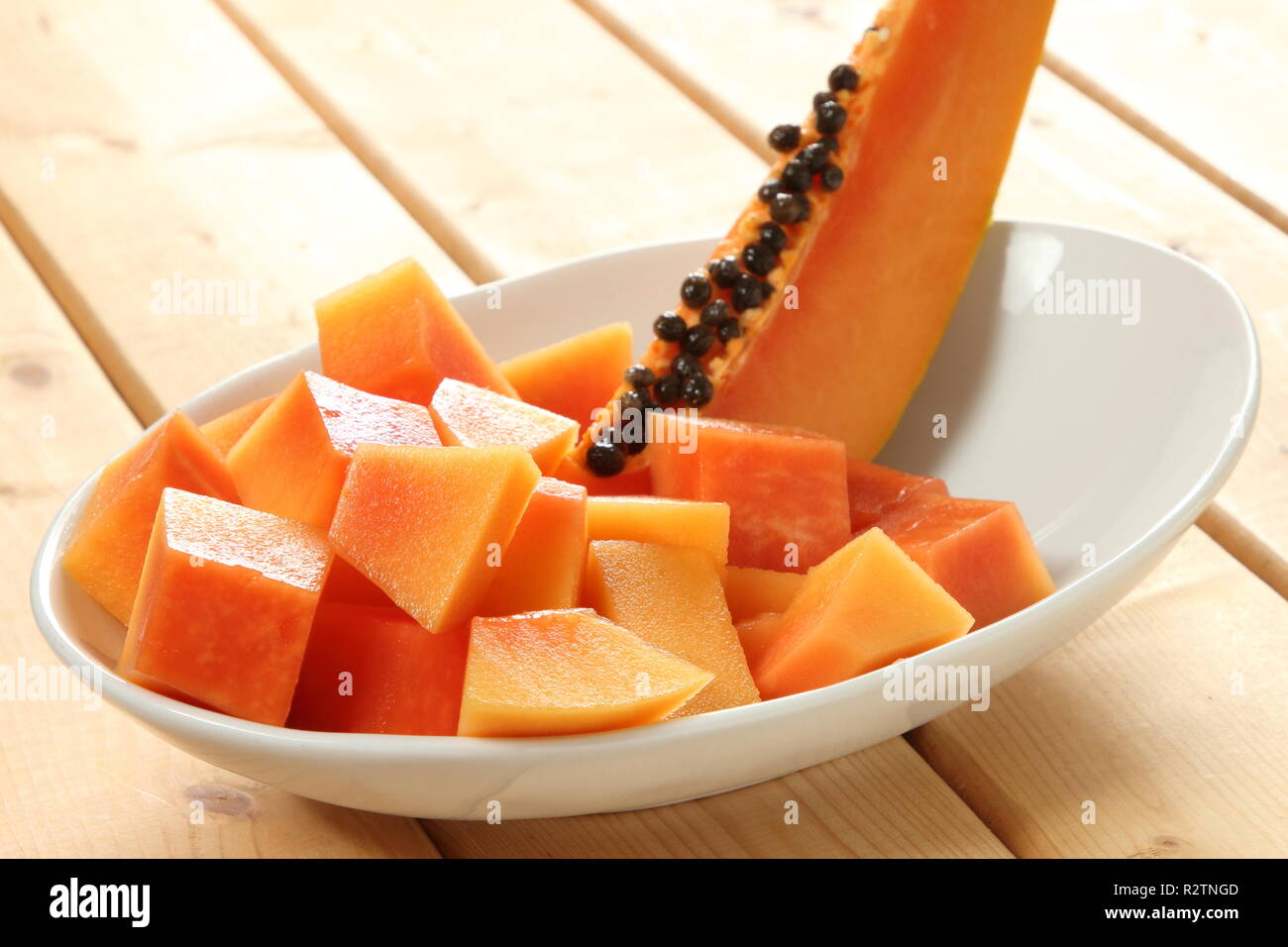 Papaya fruit cut in chunks on a wooden background Stock Photo - Alamy