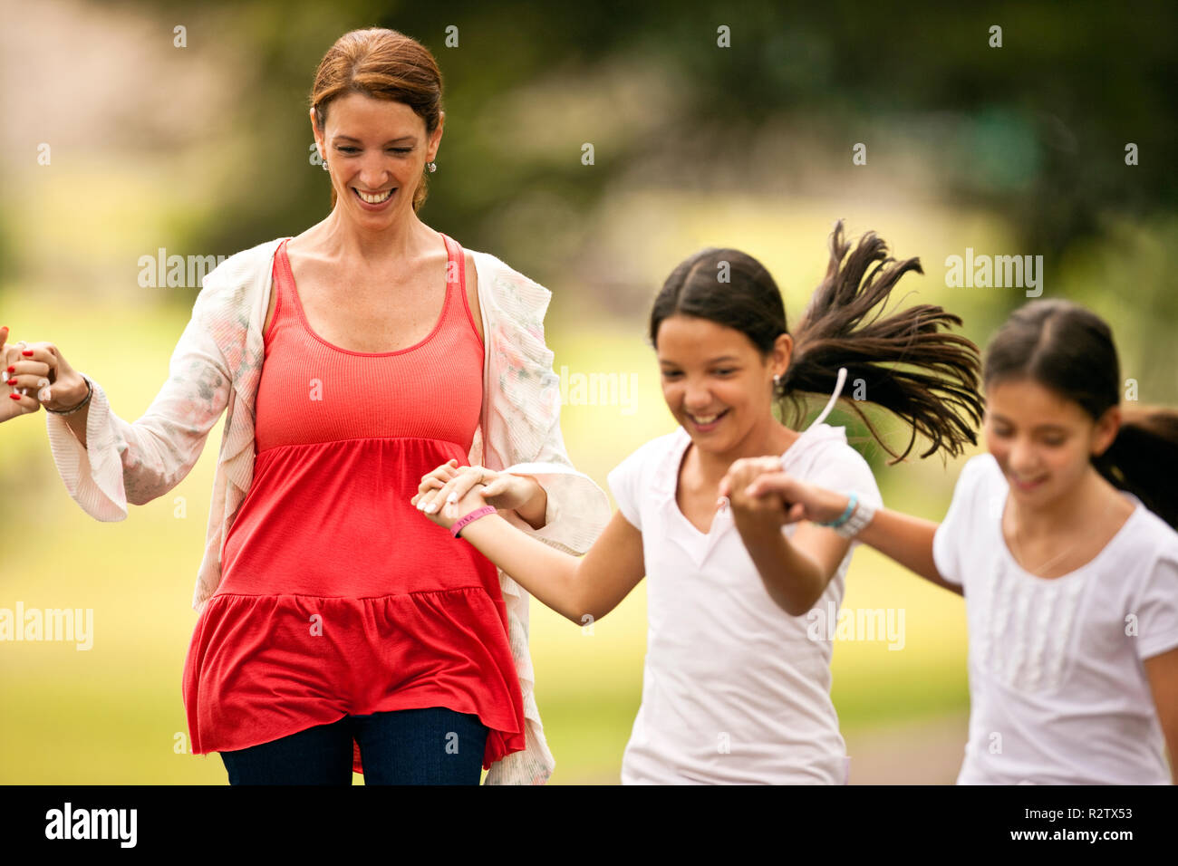 Mature woman having fun walking and holding hands with her daughters ...