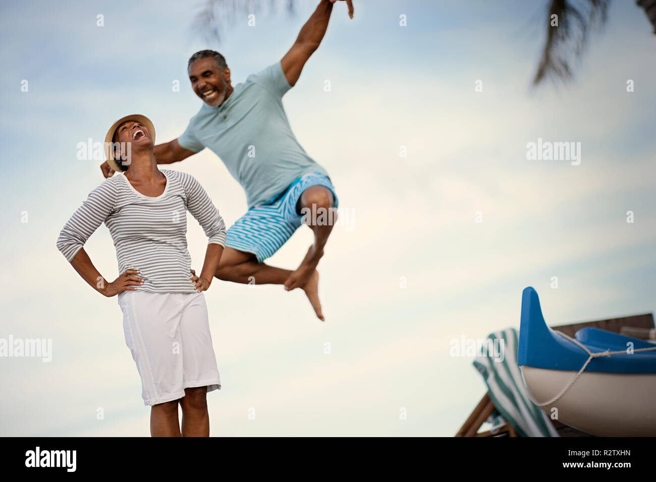 Mature couple joking around, jumping and doing Karate moves on beach ...